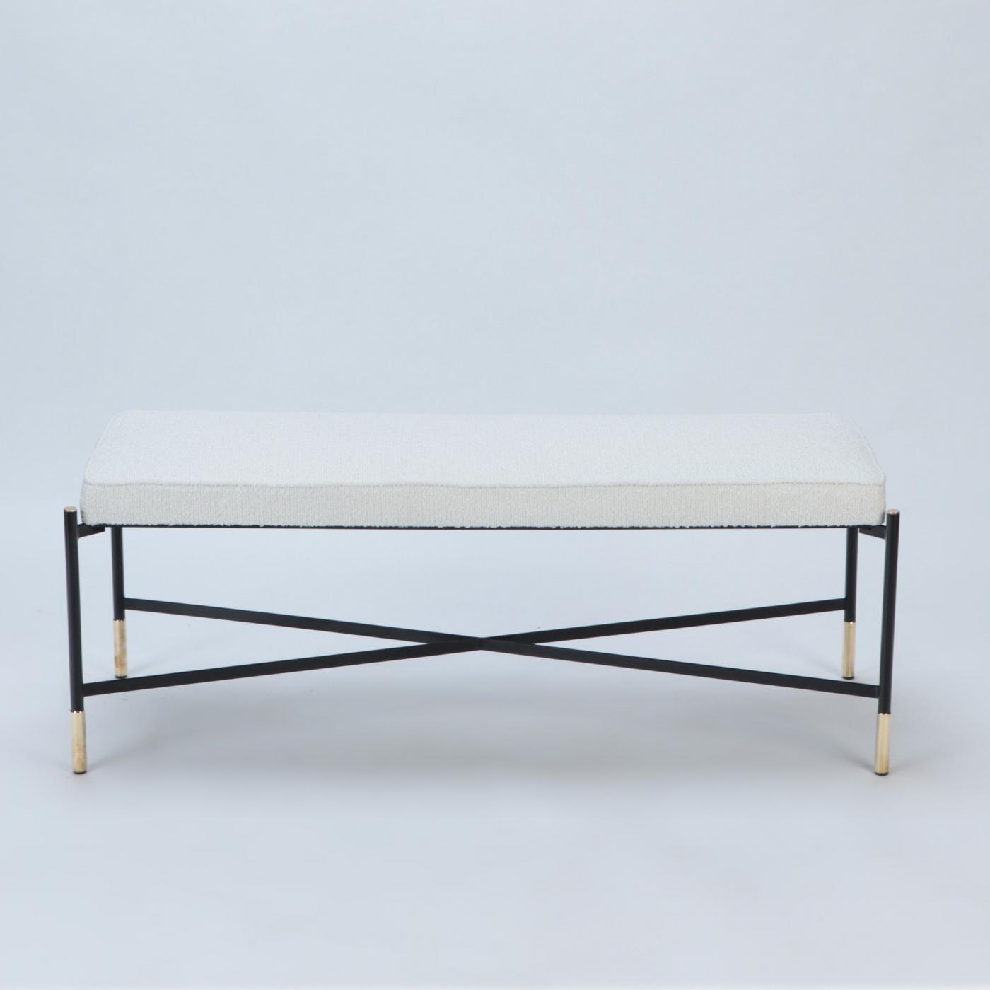 A contemporary Italian bench with cross stretchers and brass details.