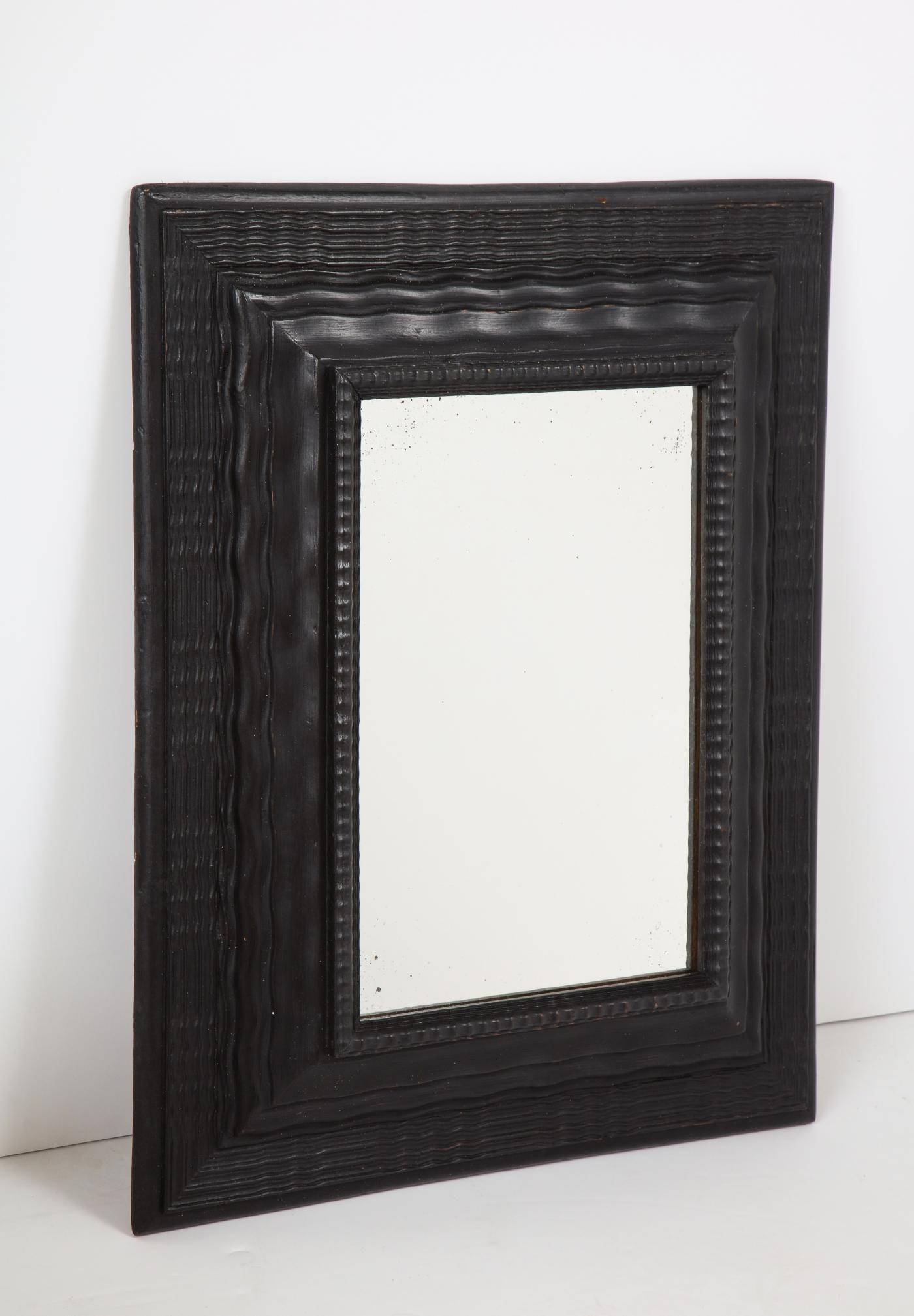 Northern Italian ripple and wave carved and ebonized mirror frame